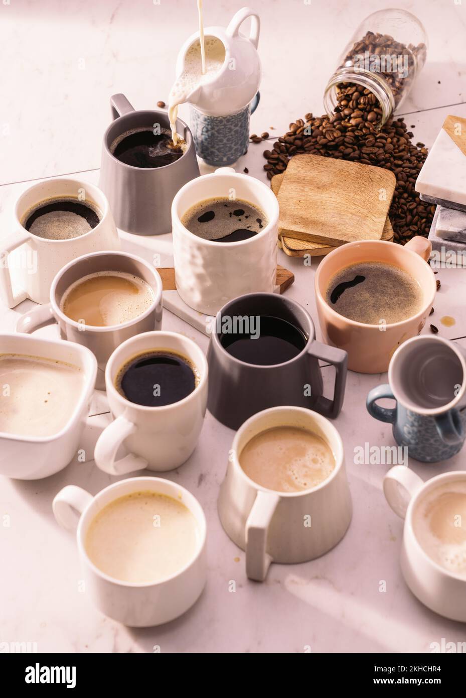A vertical shot of mugs containing different types of coffee on a white ...