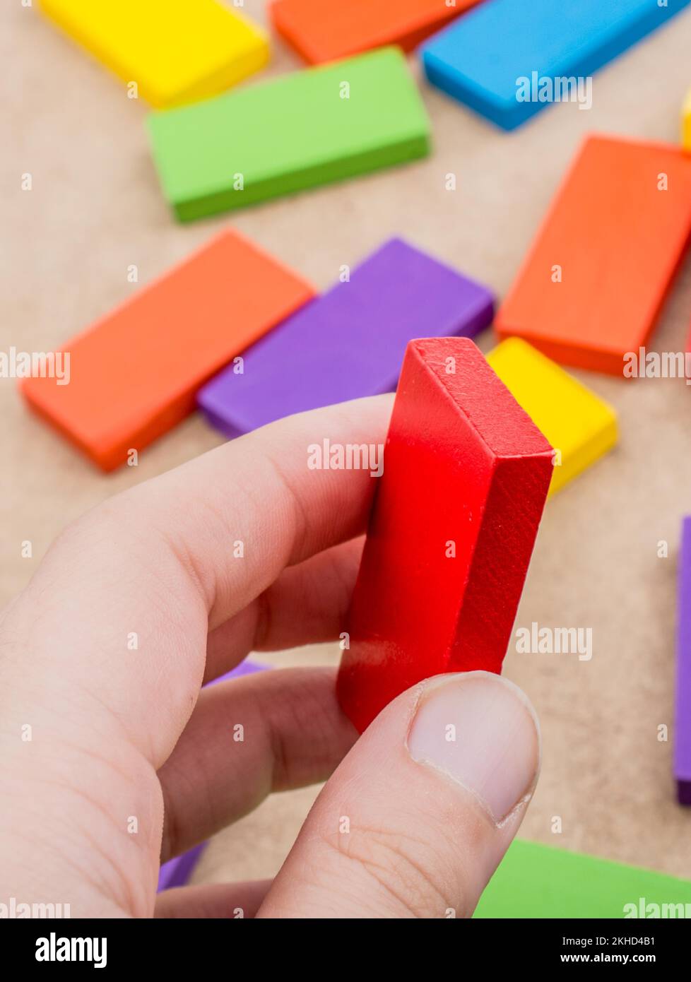 Hand holding one of the wooden blocks of various colors Stock Photo - Alamy