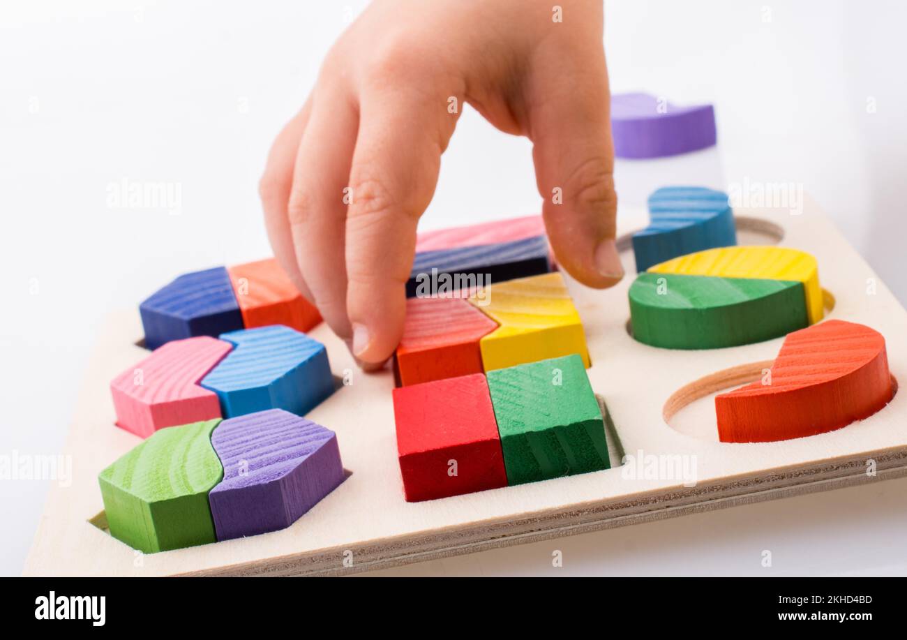 Colorful wooden pieces of a logic puzzle in hand Stock Photo - Alamy