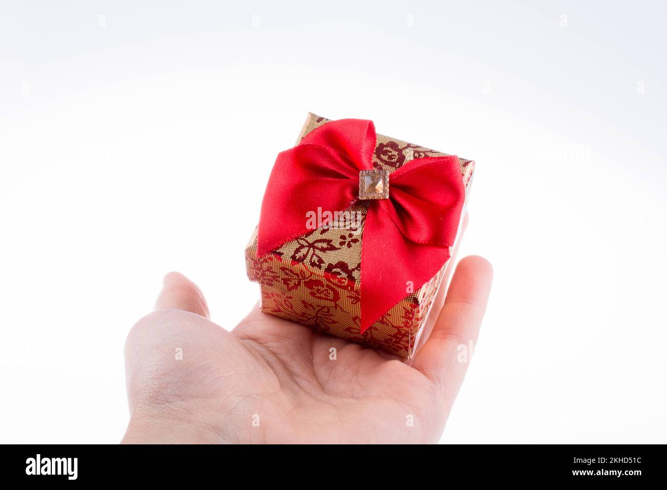Hand holding a gift box with a red ribbon Stock Photo - Alamy