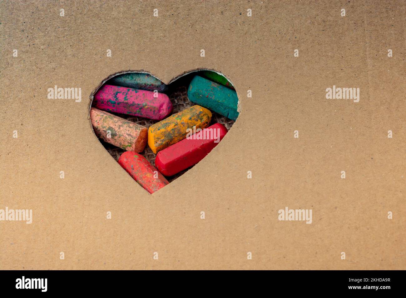 Crayons seen through heart shape cut out of cardboard Stock Photo - Alamy