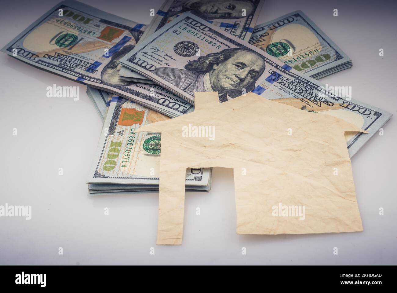 Paper house placed beside a bundle of US dollar banknote Stock Photo ...