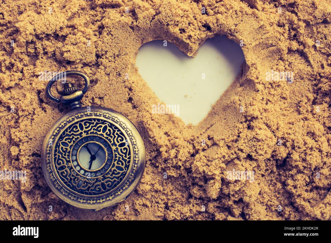 Retro style watch beside a heart shape made on sand Stock Photo - Alamy