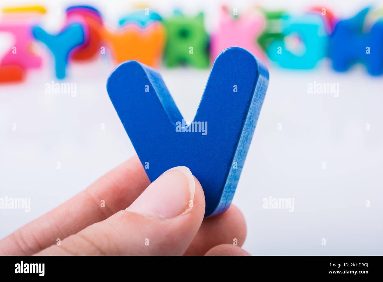 Hand holding letter cube V of made of wood Stock Photo - Alamy