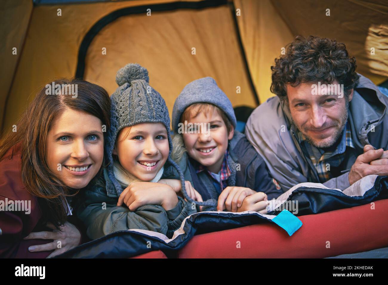 Happy campers. Portrait of smiling family of four relaxing inside their ...