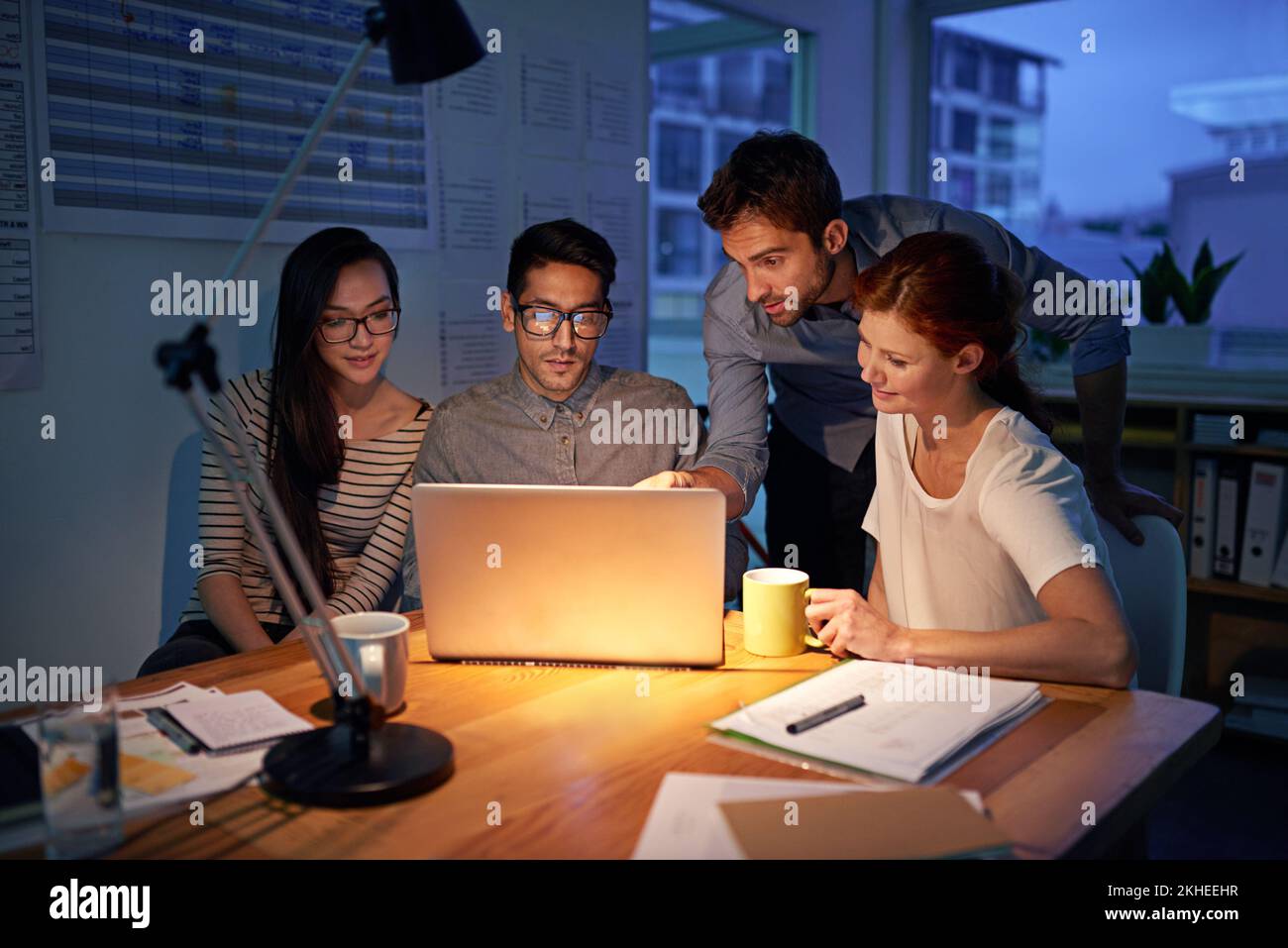 Working the late shift. four colleagues working into the night Stock ...