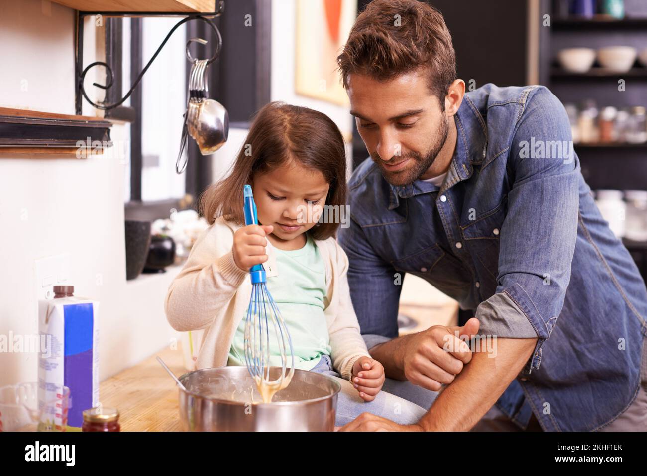Learning the basics of breakfast. A cute little girl helping her dad ...