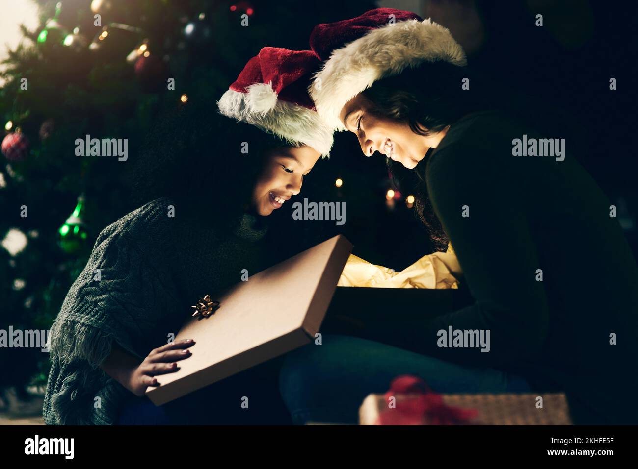 Christmas, holiday and mother and girl with present opening magic gift ...