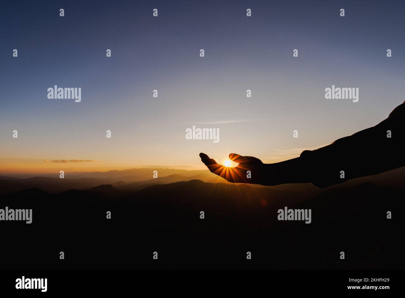 silhouette of man rise hand up praying on top of mountain and sunset ...