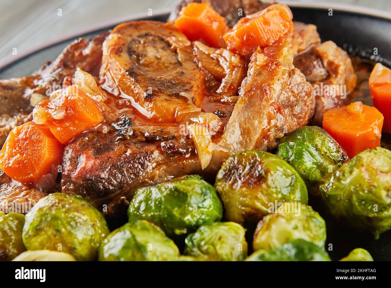 French recipe Brussels sprouts with ossobuco meat on black plate on ...