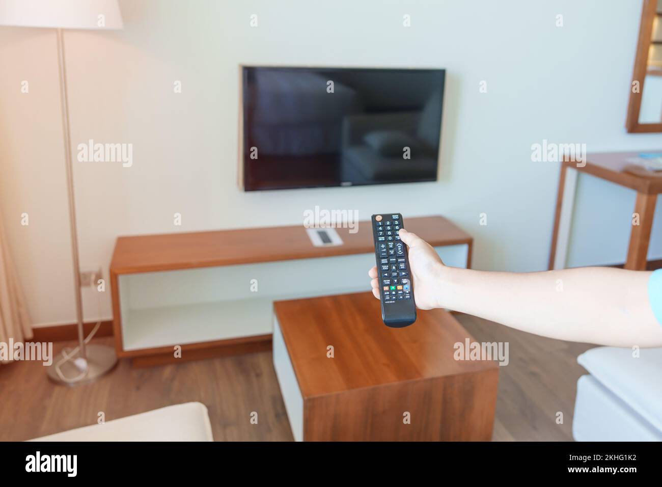 hand using remote controller for adjust Smart TV inside the modern room ...