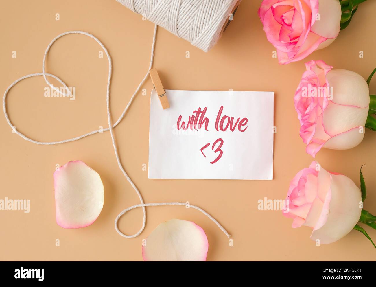 Tender pink roses with spool of white cotton rope in heart shape on ...