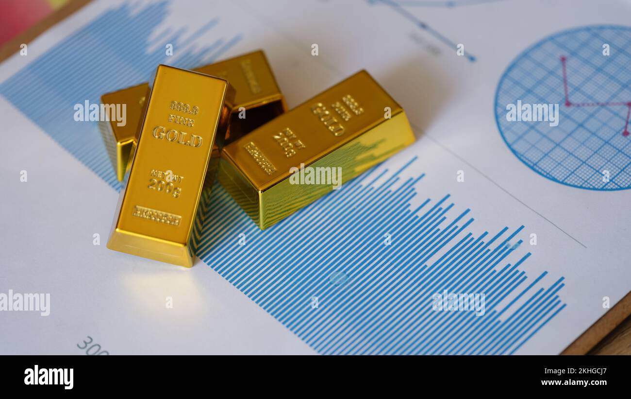 Small gold ingots on financial statistics document with charts and ...