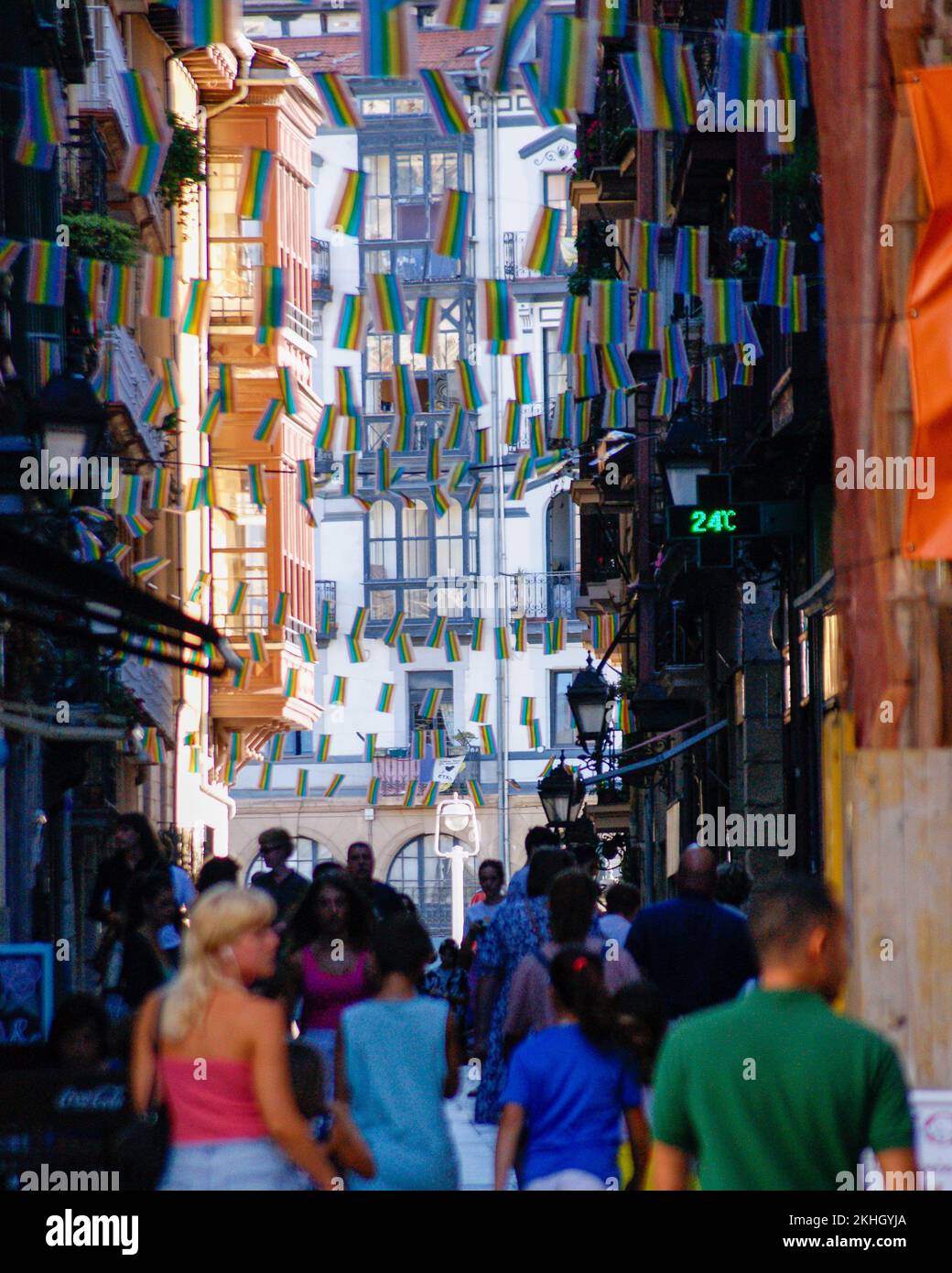 A vertical of people walking on a street in Bilbao with hanging flags ...