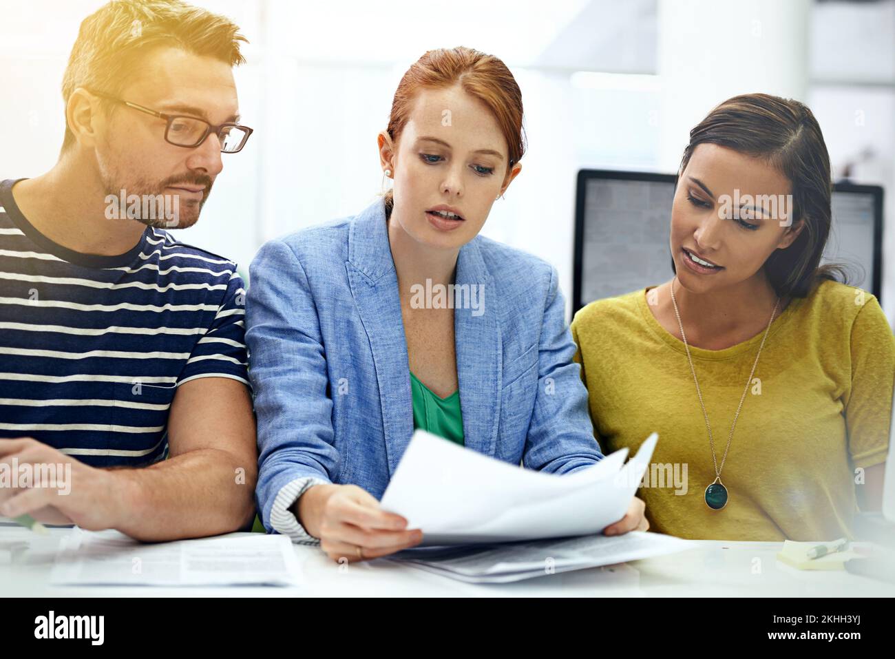 Going over the paperwork. three colleagues looking over some paperwork ...