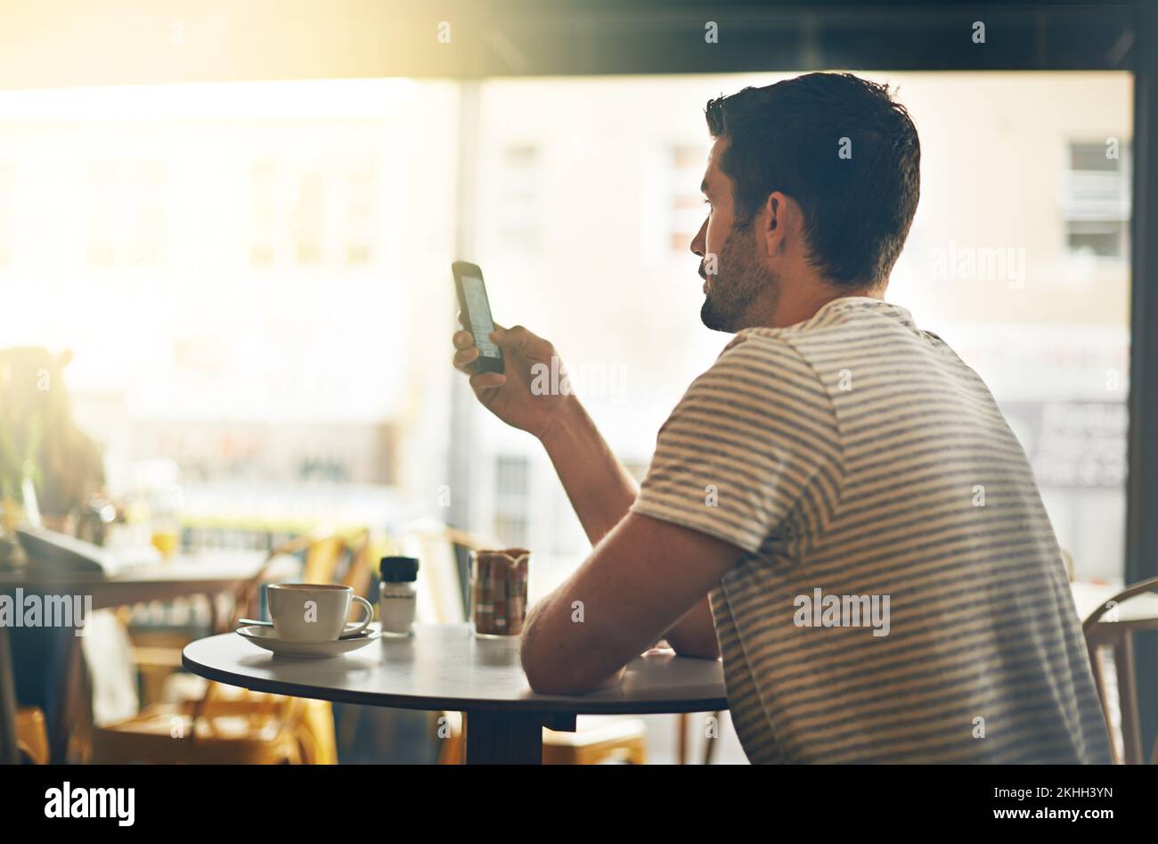 Connecting to the cafes wifi network. a young man using his cellphone ...