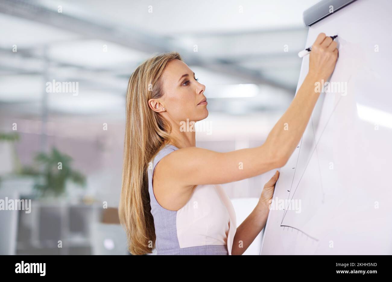 Presenting the perfect business plan. a young businesswoman writing on ...