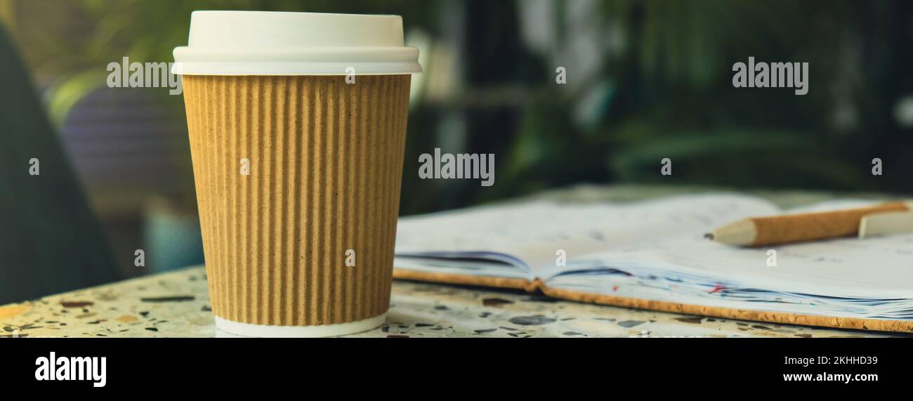 Hot latte coffee in craft recycling paper cup with paper notebook. A ...
