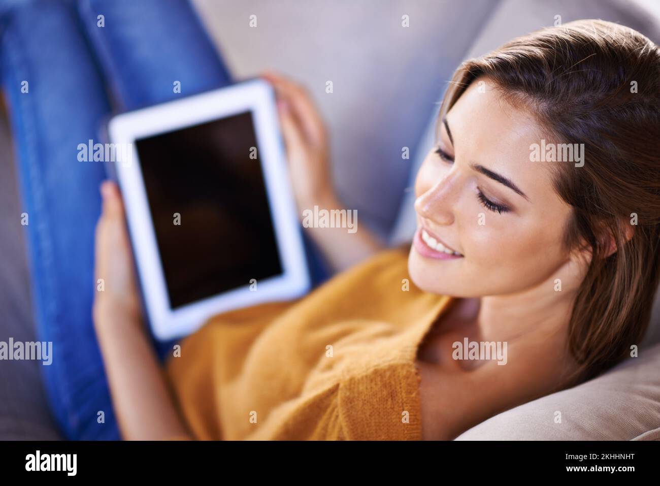 Just passing the time. an attractive young woman relaxing on the sofa ...