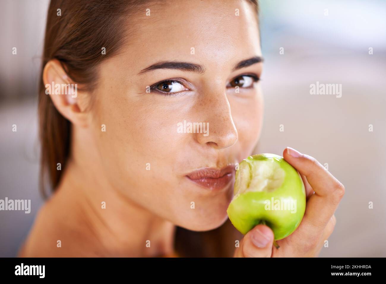 Happy snacking. An attractive young woman biting into a green apple ...