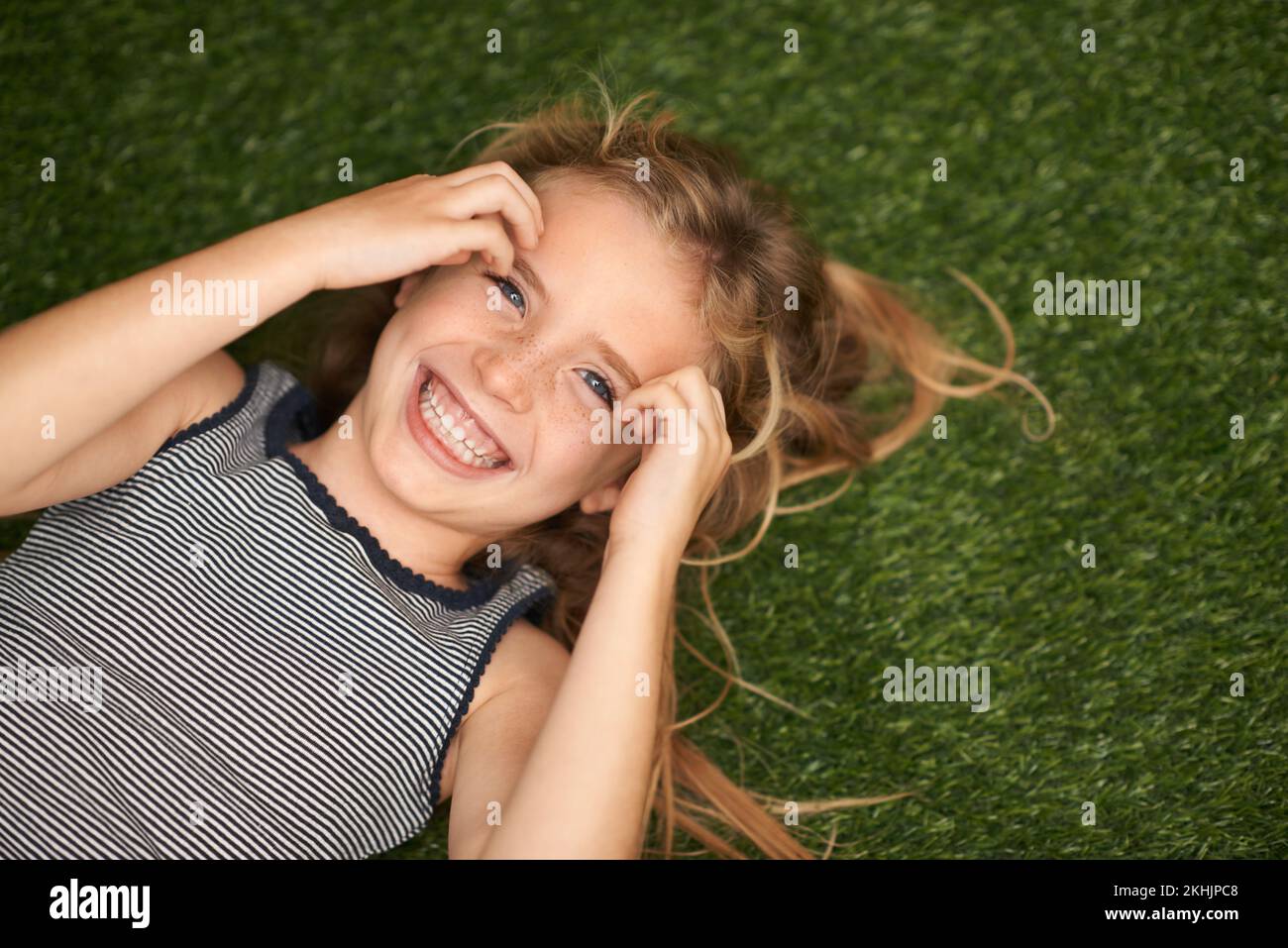 Outdoor joy. High angle portrait of a cute little girl lying on her ...