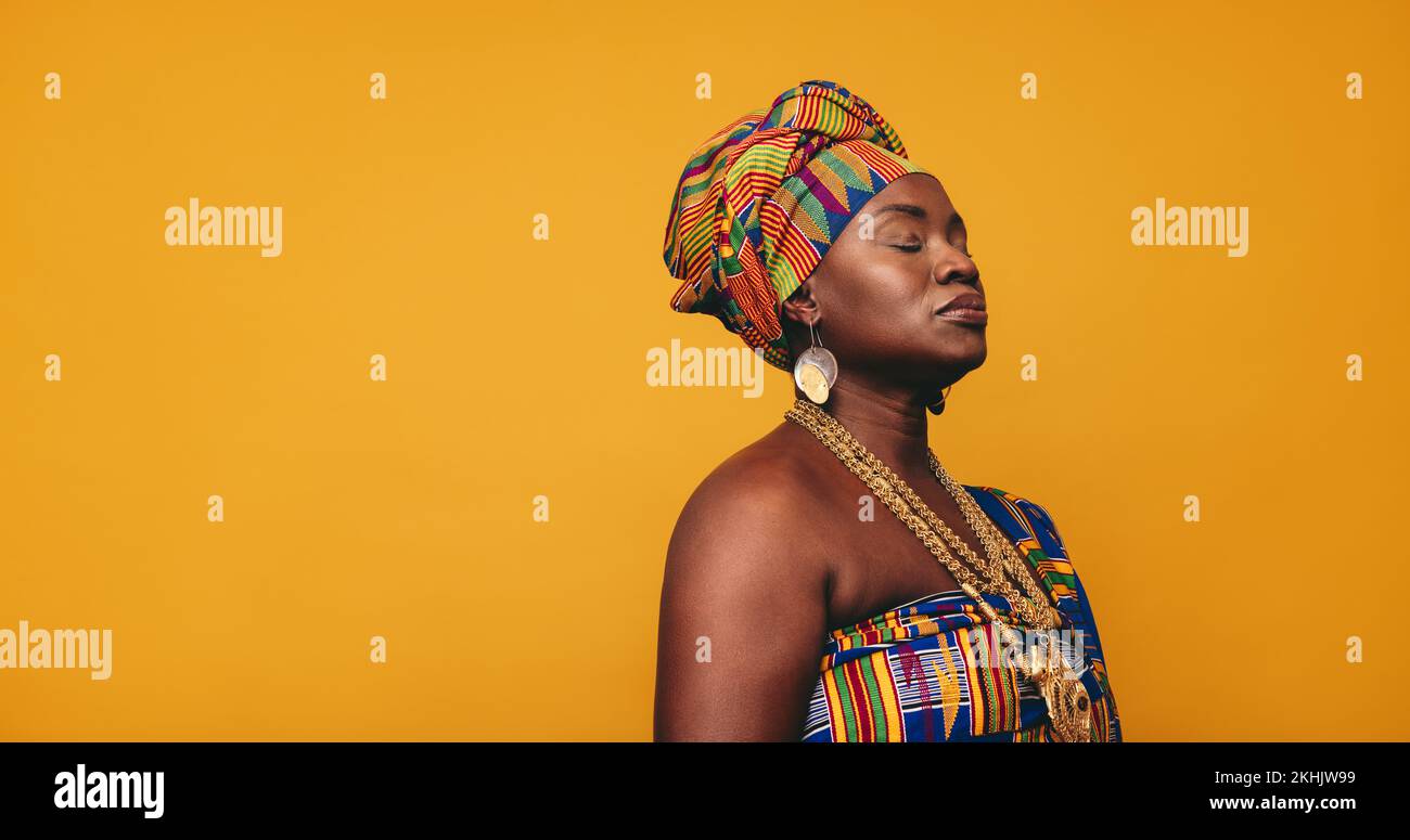 Ghanaian woman wearing traditional clothing against a yellow background ...
