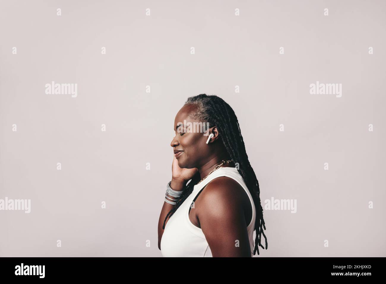 Trendy middle-aged woman enjoying her favourite music on bluetooth ...