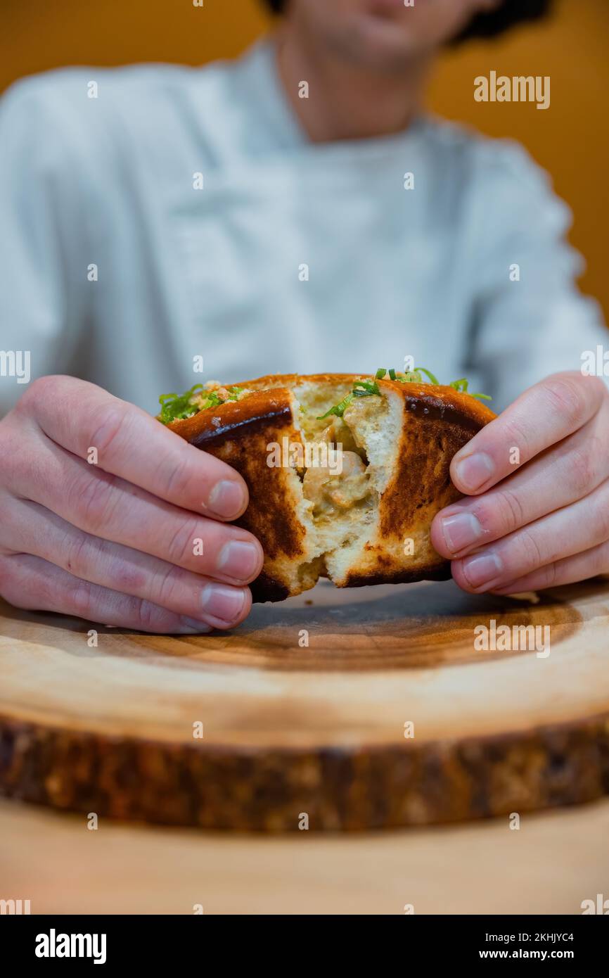 The vertical shot of someone splitting the stuffed bread with hands ...