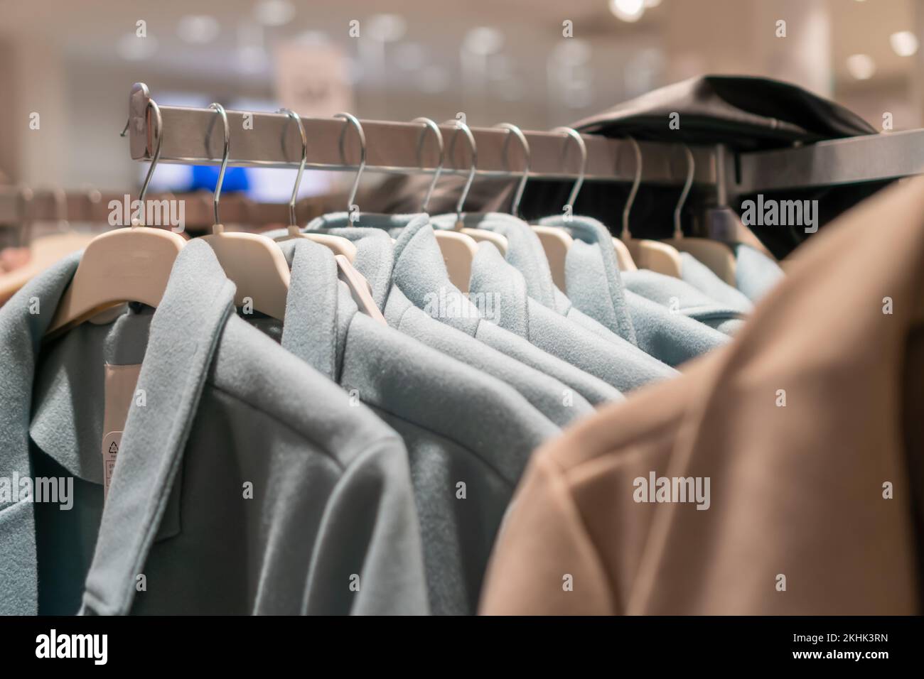 Blue coats hang on hangers in the mall. Classic women's fashion ...