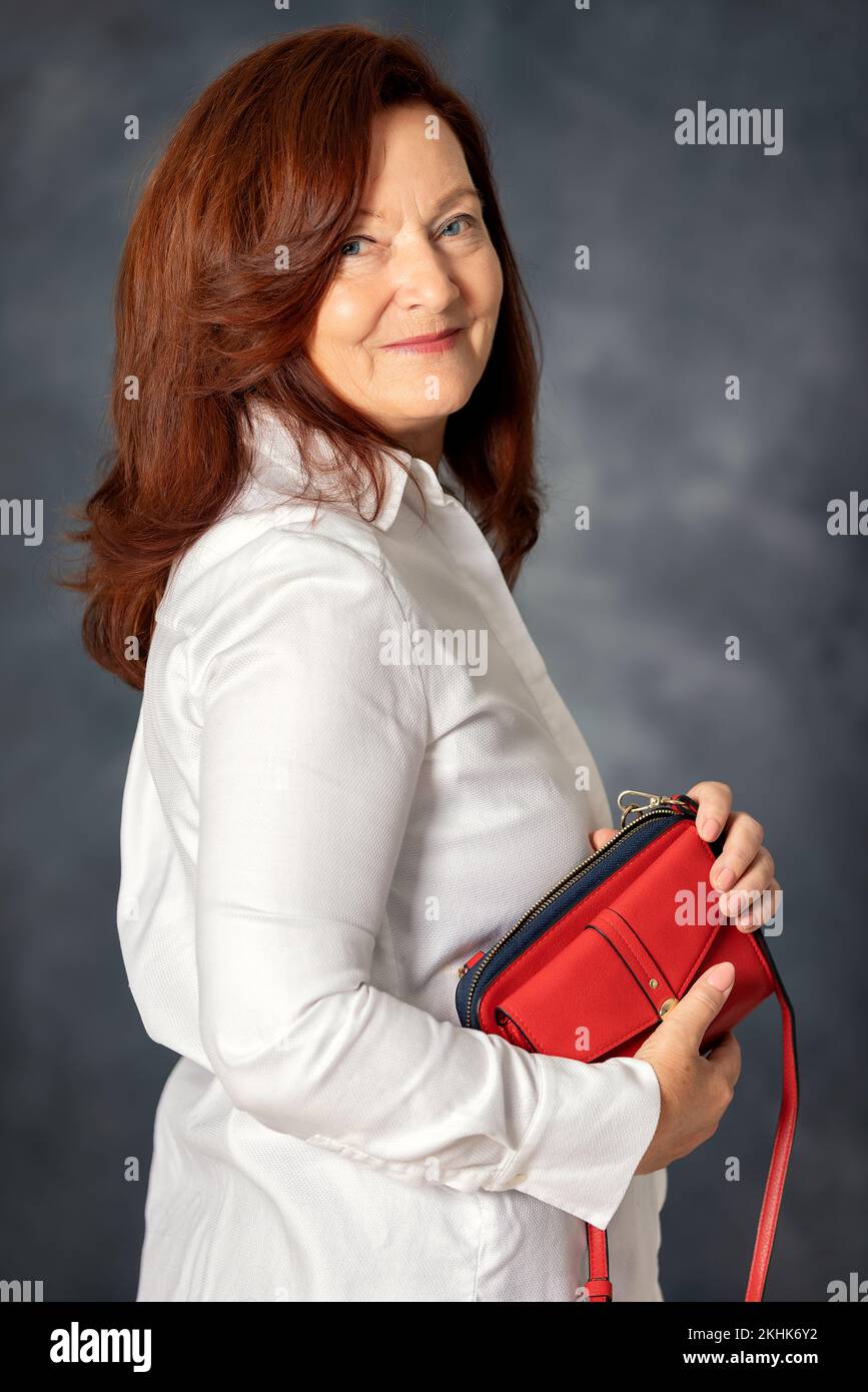 Portrait of stylish adult 60s year old woman on grey background. Confident stylish european ...