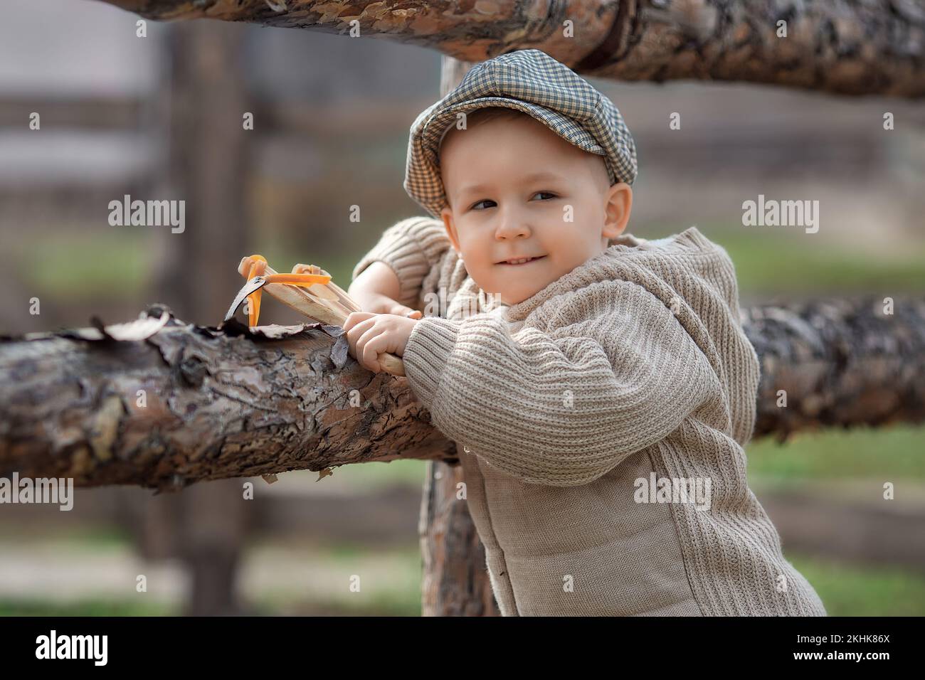 Bully boy kid with a slingshot aims at someone near a fence in the ...