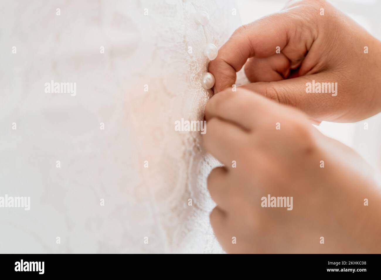 Morning preparation of the bride. Close-up of a bridesmaid, fastening a ...