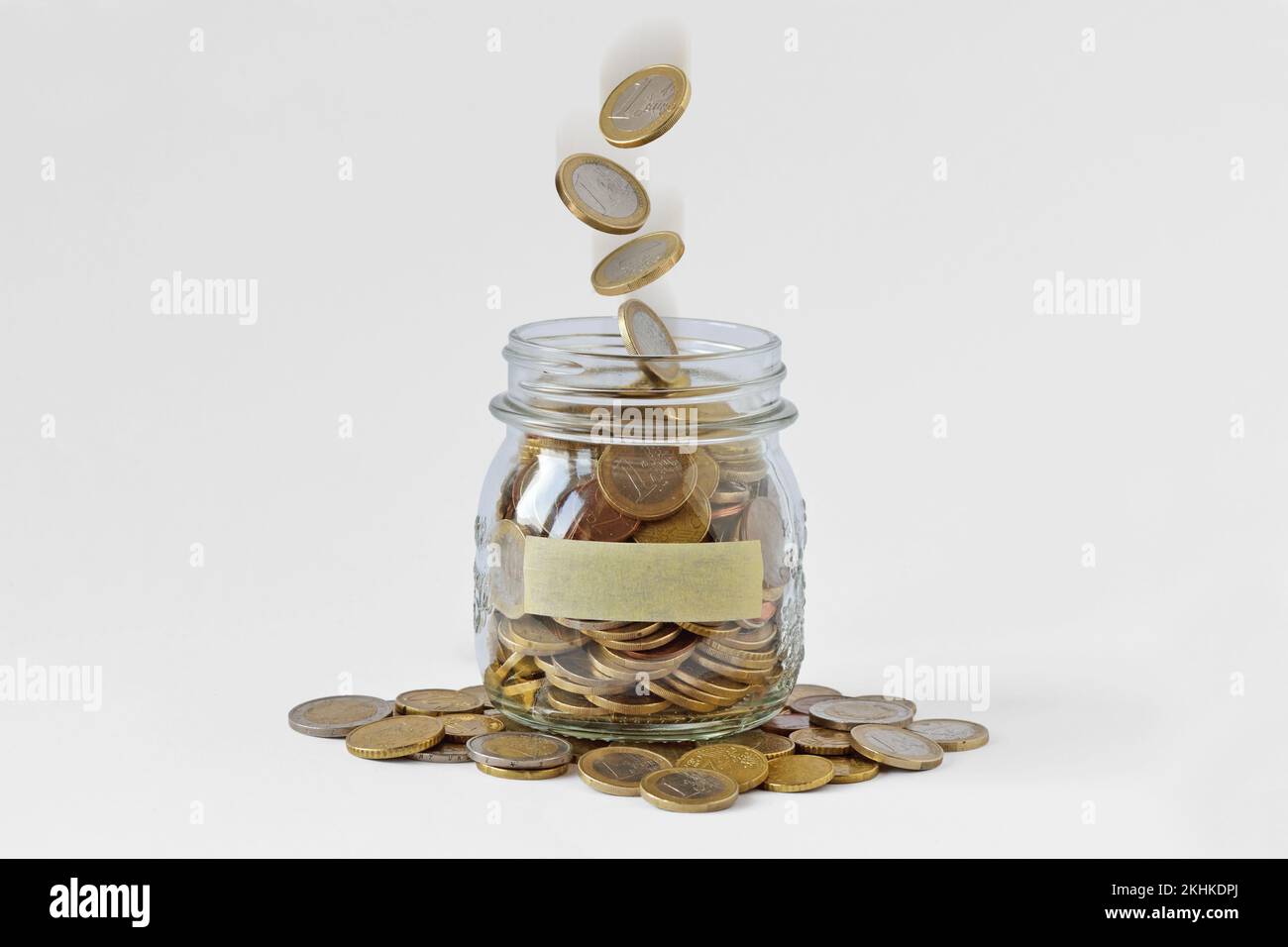 Money jar with blank label and falling coins on white background ...