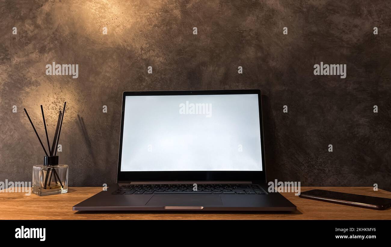 Front view of open laptop with blank white screen monitor on desktop ...