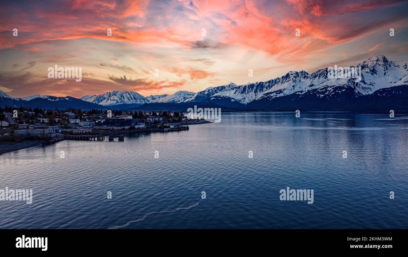 A breathtaking view of the lake surrounded by snowy mountains during scenic sunset in Seward ...
