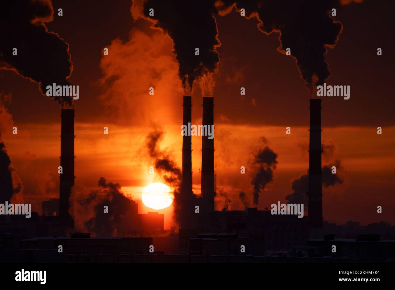 Coal-fired power station with smoking chimneys against red sunset sky ...
