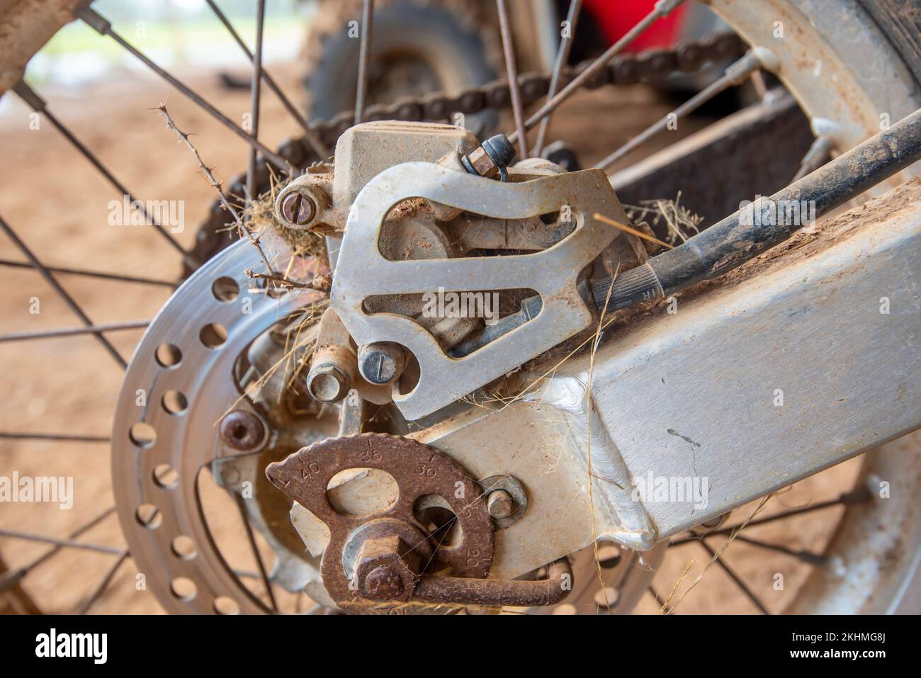 A close up of the rear wheel of a farm motorbike with grass and burs ...