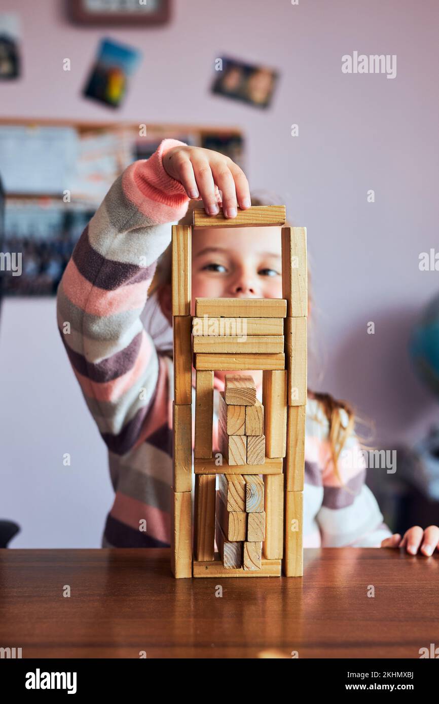 Little girl preschooler playing with wooden blocks toy building a tower ...