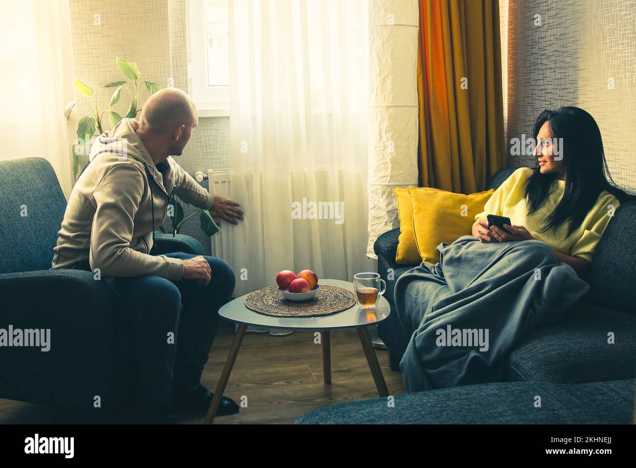 Caucasian couple at home sit in living room check heating touch ...