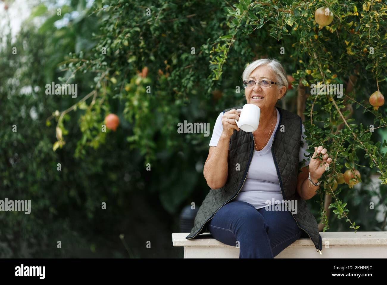 Senior grey hair woman having tea in sunny garden stunning countryside ...