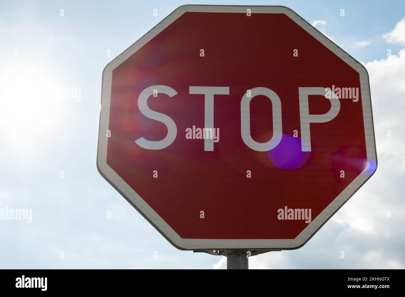 Red stop sign on metal pole on street. Road attention sign on cloudy ...