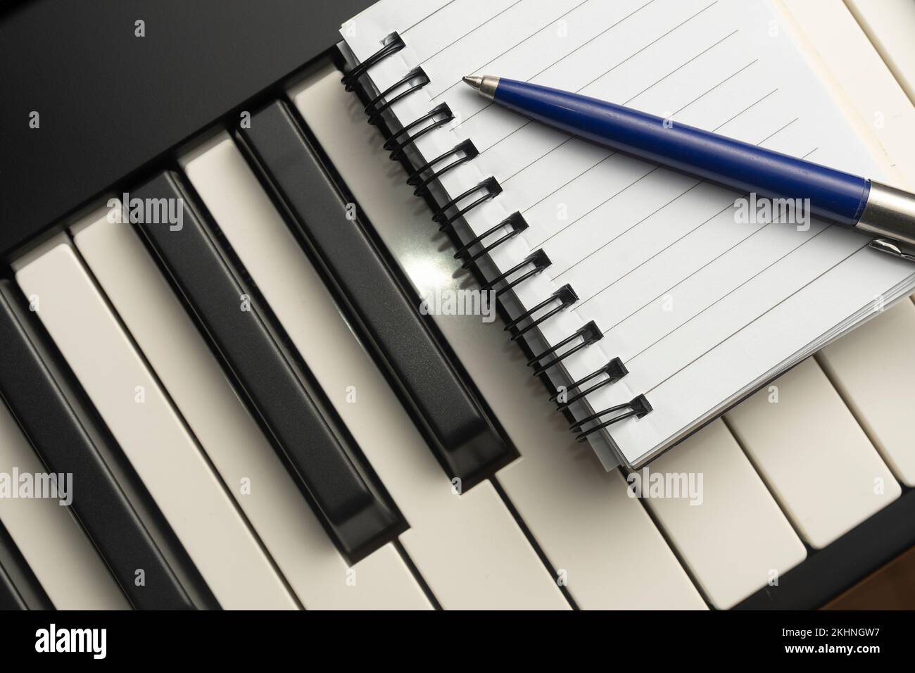 Music composition concept: a notepad and a pen leaning on the keyboard ...