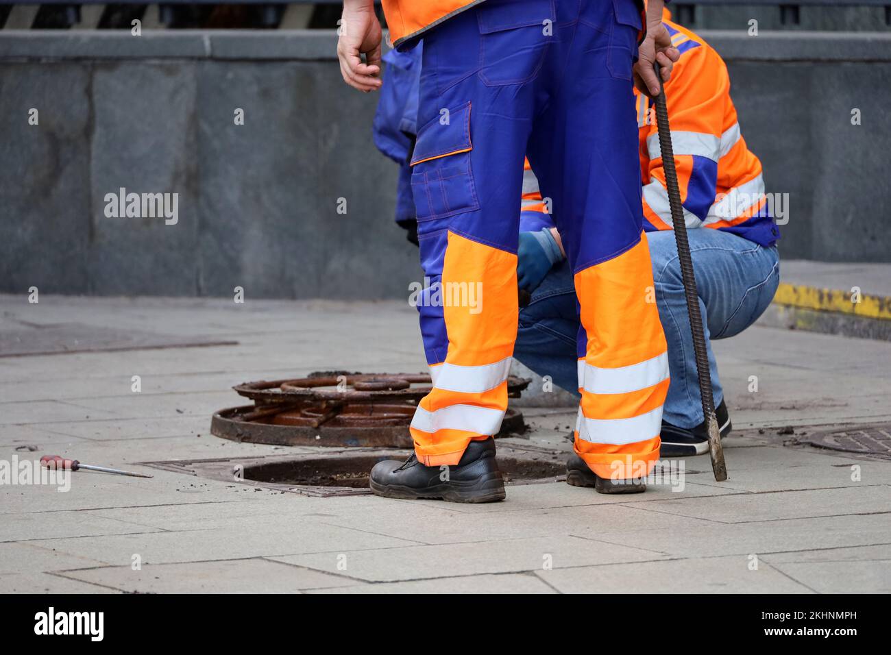 Workers over the open sewer hatch on a street. Concept of repair of ...
