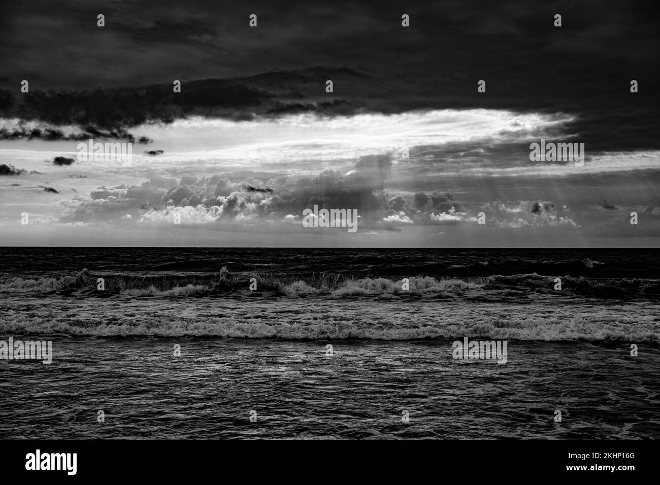 A black and white shot of sun's rays break through thick clouds ...