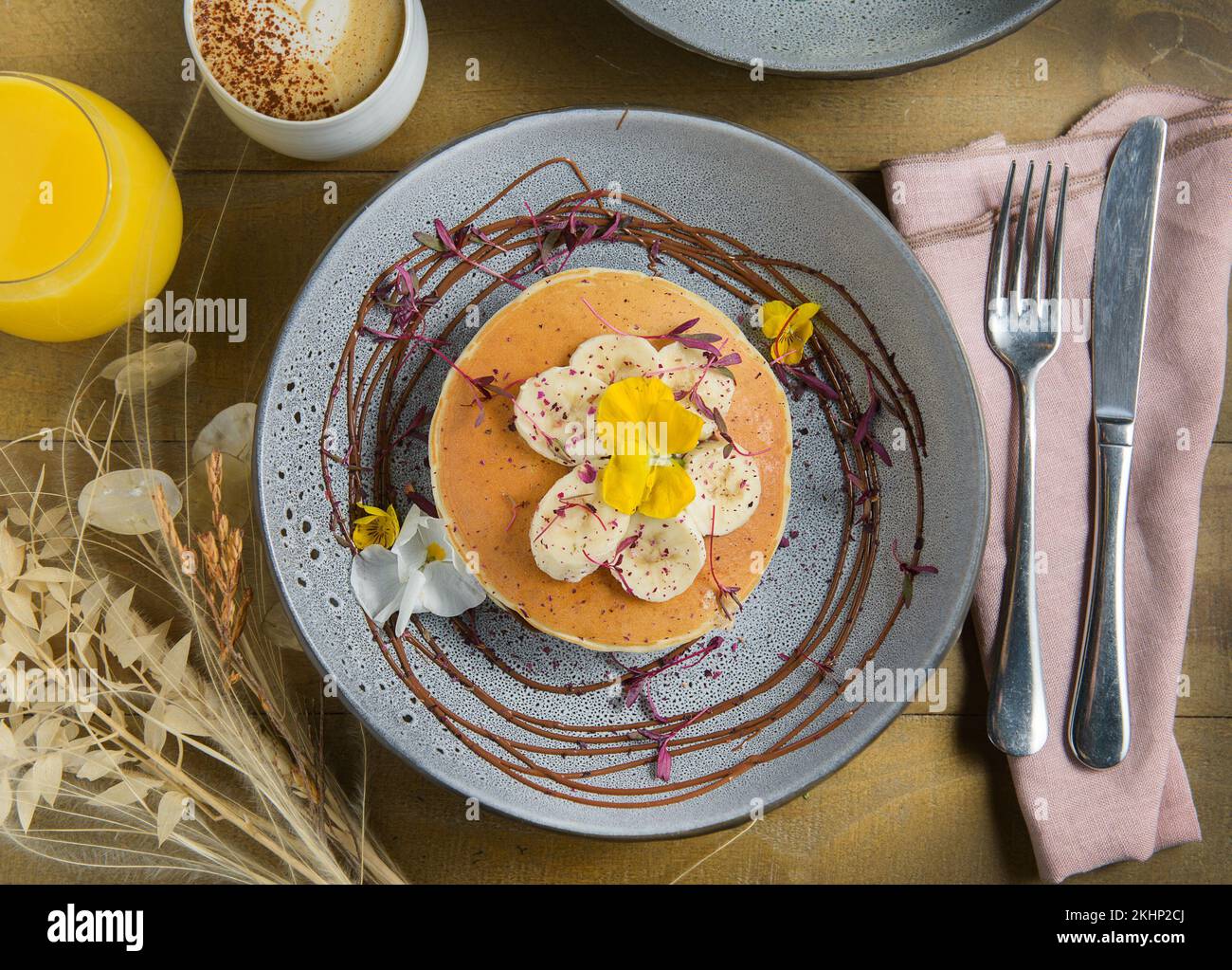 A top view of a pancake with a flower on the top and round sprinkled ...