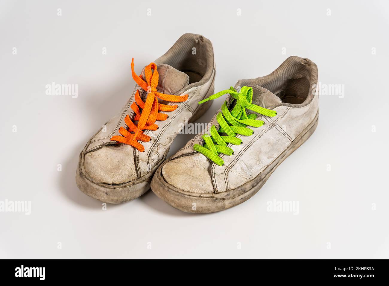 worn old torn white sneakers with colored laces on a white background ...