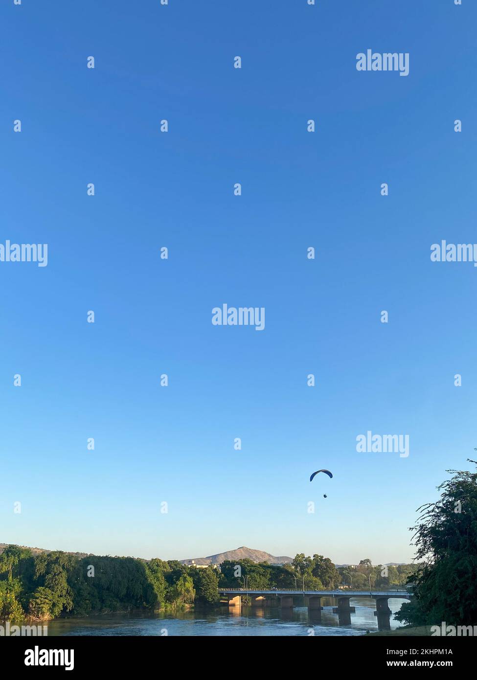 A vertical shot of a person on a parachute flying in the sky over the ...