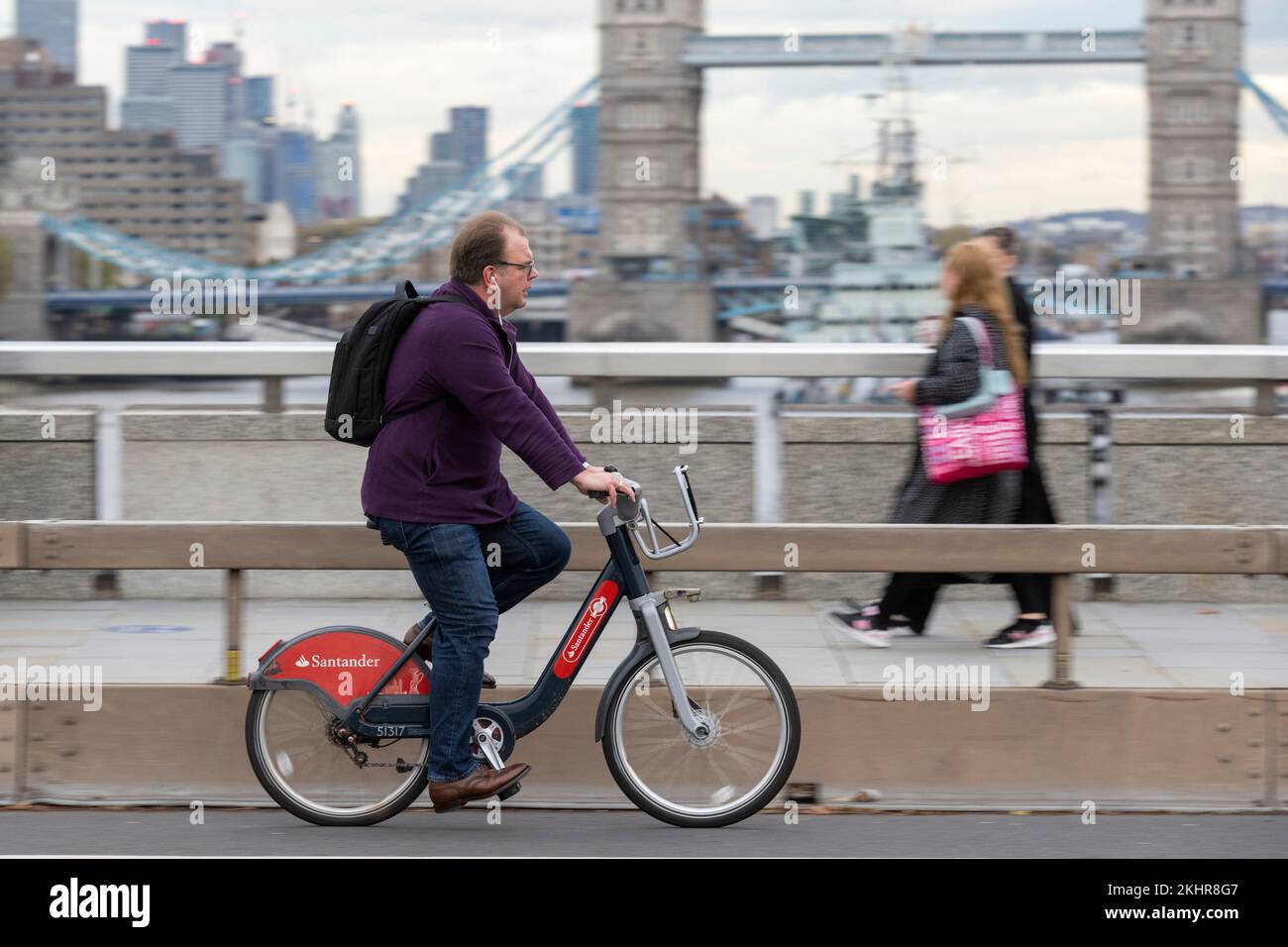 A man cycling during the rush hour, across London Bridge, on a Transport for London Santander ...