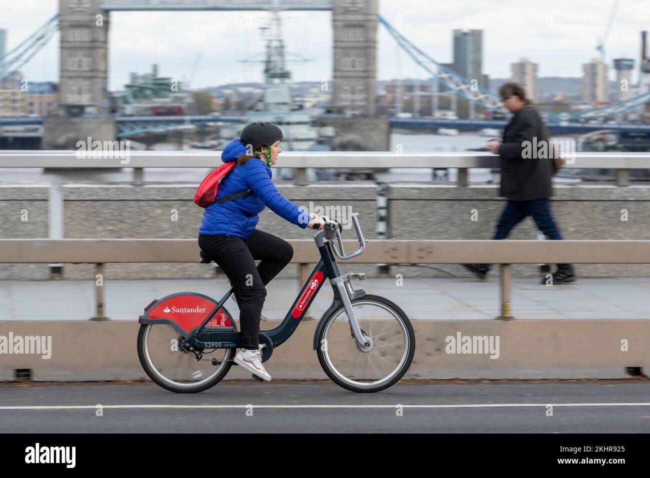 A woman cycling during the rush hour, across London Bridge, on a Transport for London Santander ...
