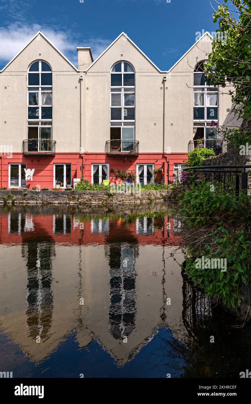 A vertical shot of three connected buildings with their reflection in ...